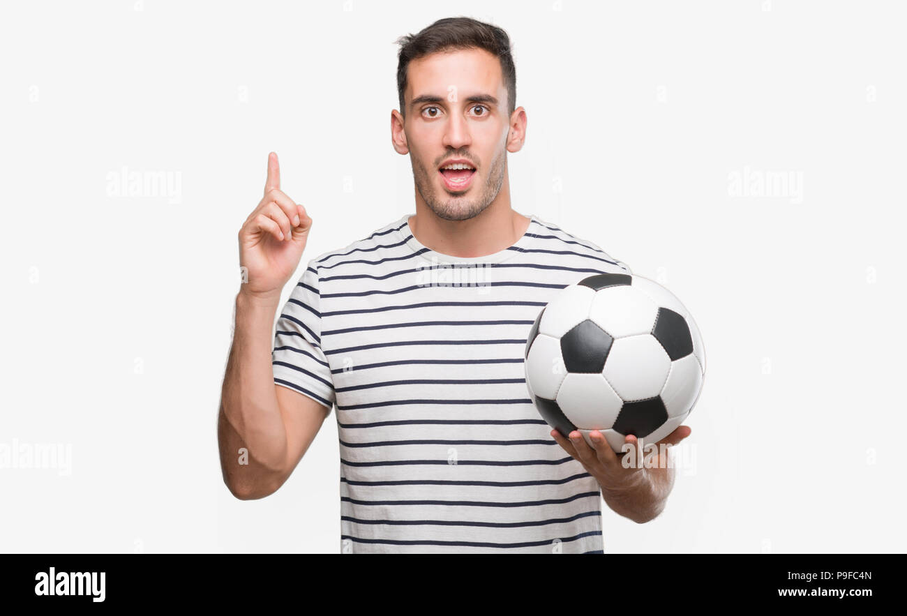 Handsome young man holding soccer football surprised with an idea or ...