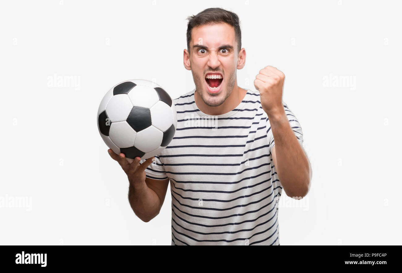 Handsome young man holding soccer football annoyed and frustrated ...
