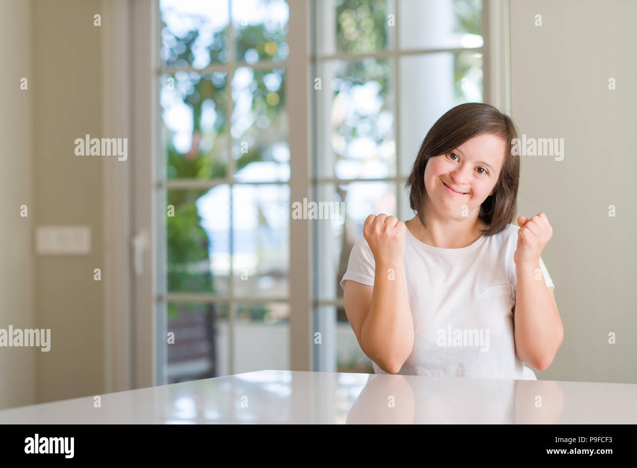 Down syndrome woman at home very happy and excited doing winner gesture ...