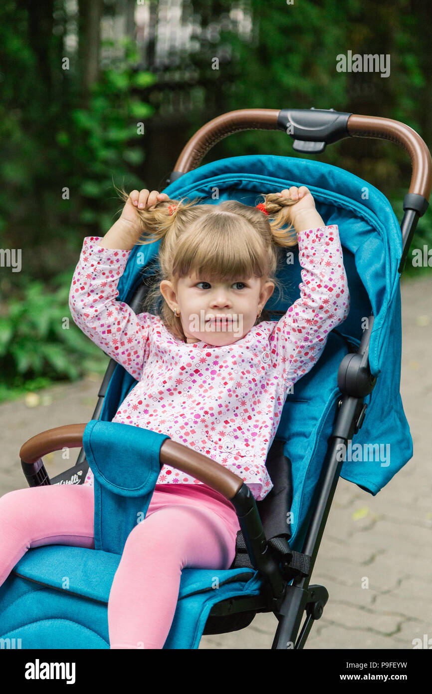 Little girl is sitting in a pram in a beautiful park Stock Photo - Alamy