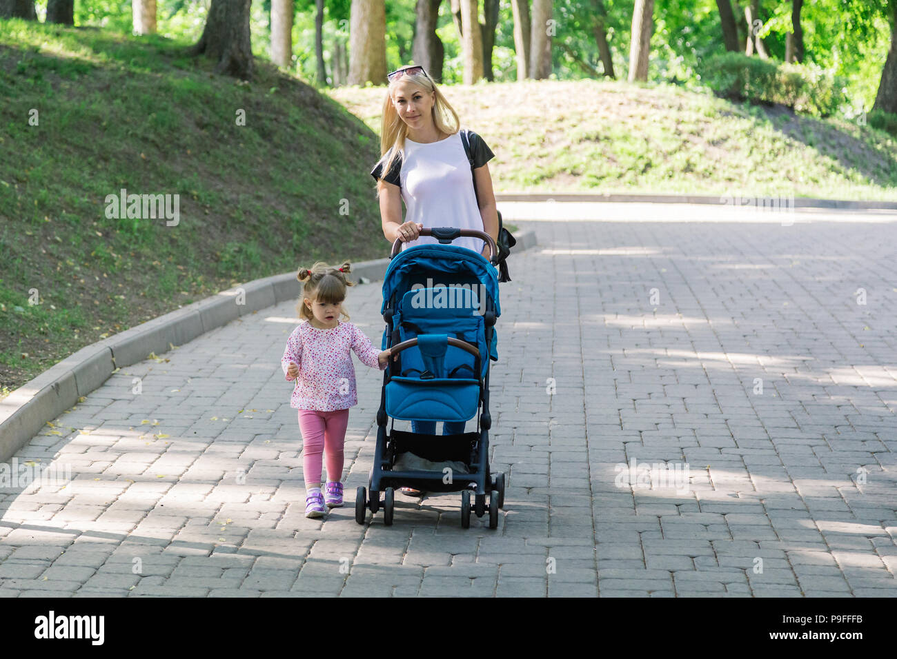 Mother walking while pushing a stroller in the park Stock Photo - Alamy