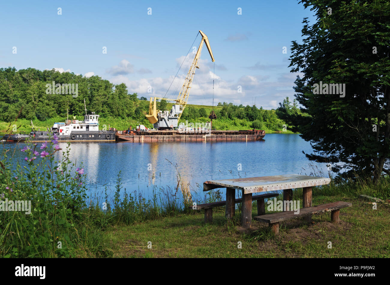 Boat, barge and excavator float on the river Western Dvina Stock Photo ...