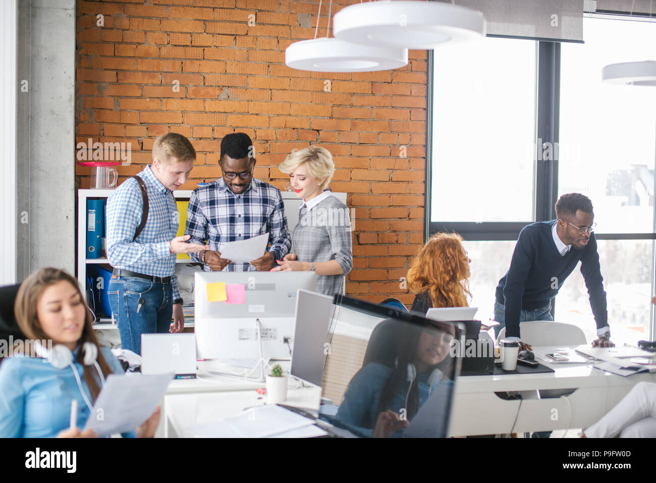 young positive staff members holding and looking at successful contract ...