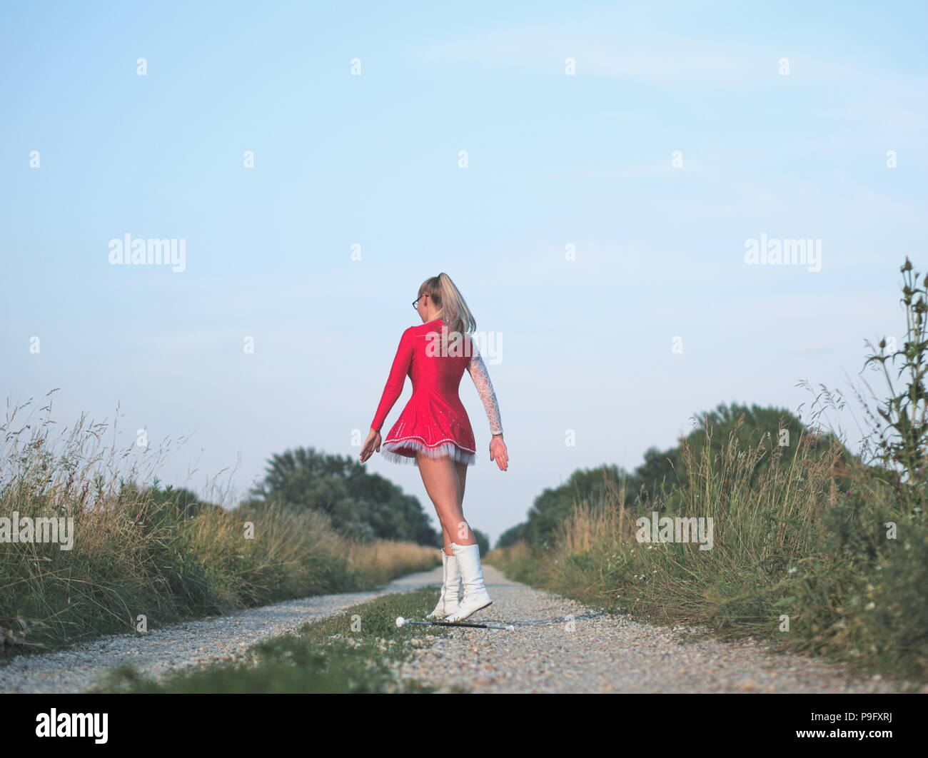 Bespectacled Blonde Teen Majorette Girl Twirling Baton Outdoors in Red ...