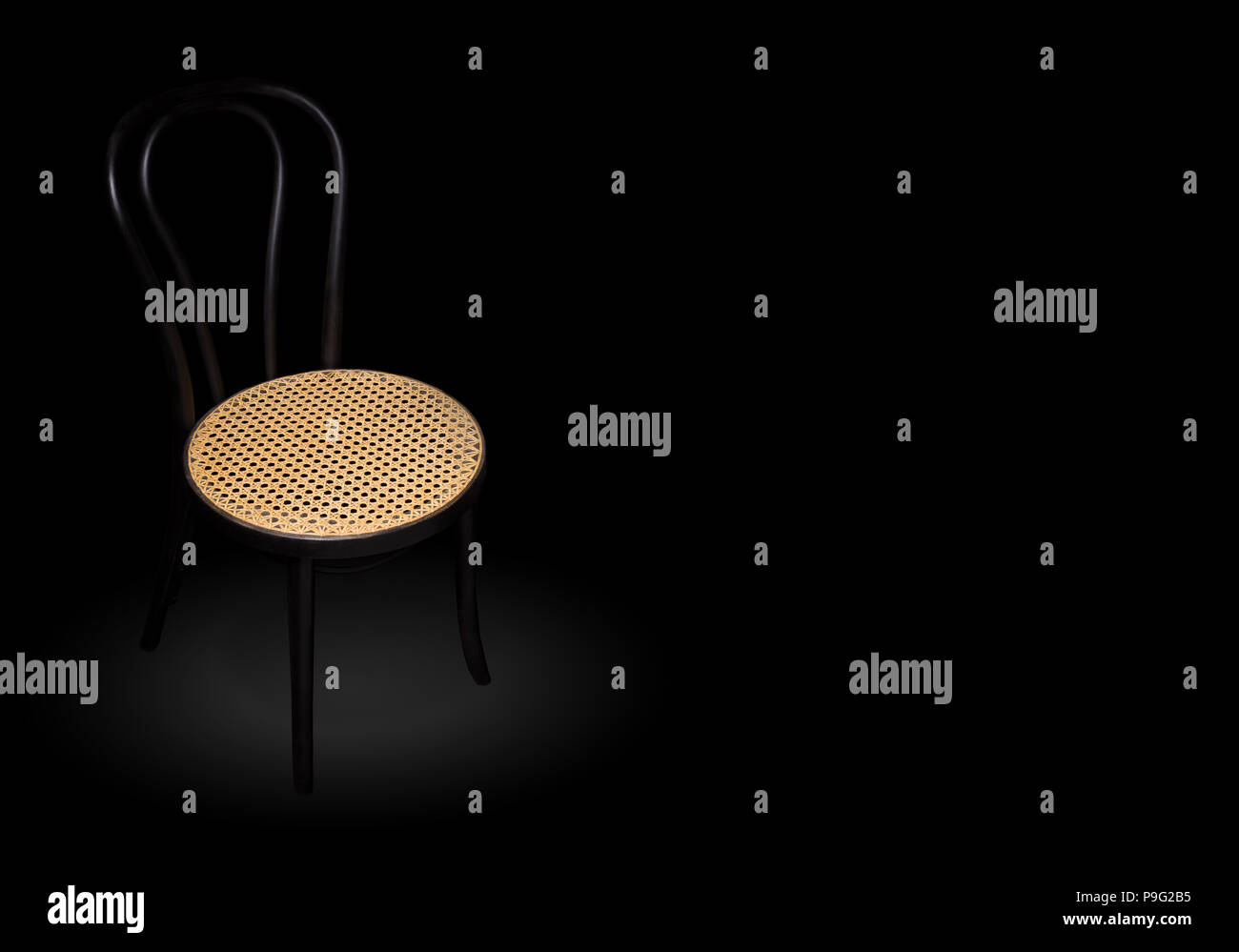 Lonely chair at the empty room. Wooden Chair in spotlight in dark black ...