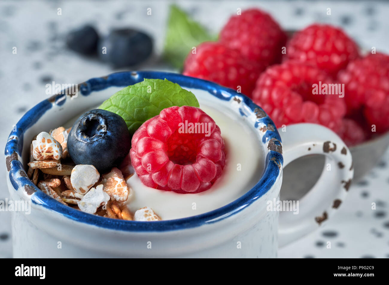 Yogurt with muesli, raspberry and nuts, healthy dessert on light blue ...