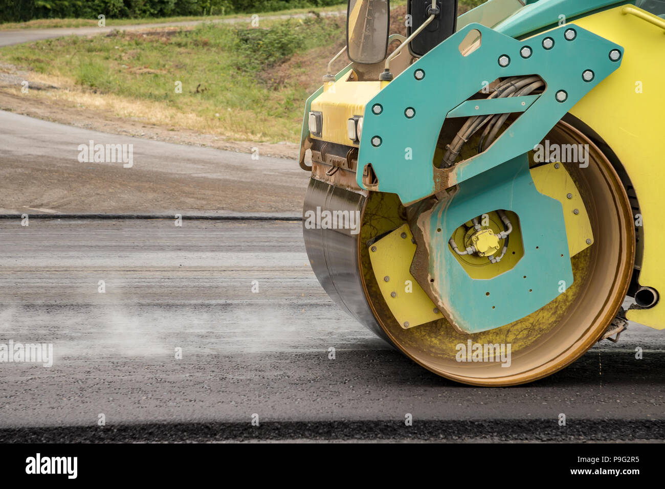 New asphalt road. the yellow road roller working on the new road with ...