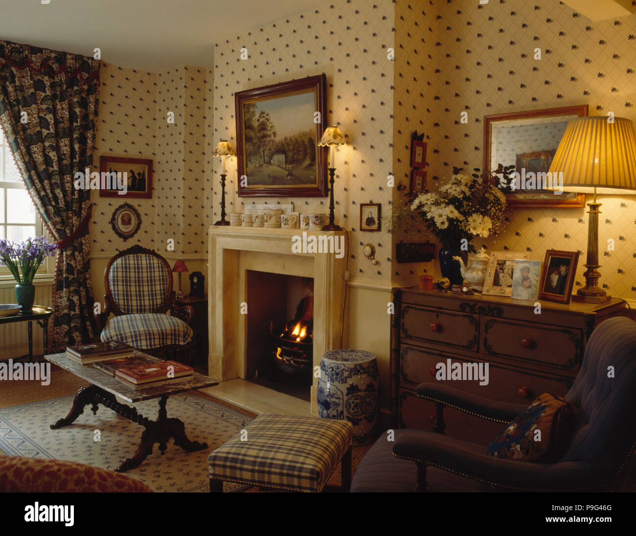 Lighted fire in fireplace of living room with spotted neutral wallpaper ...