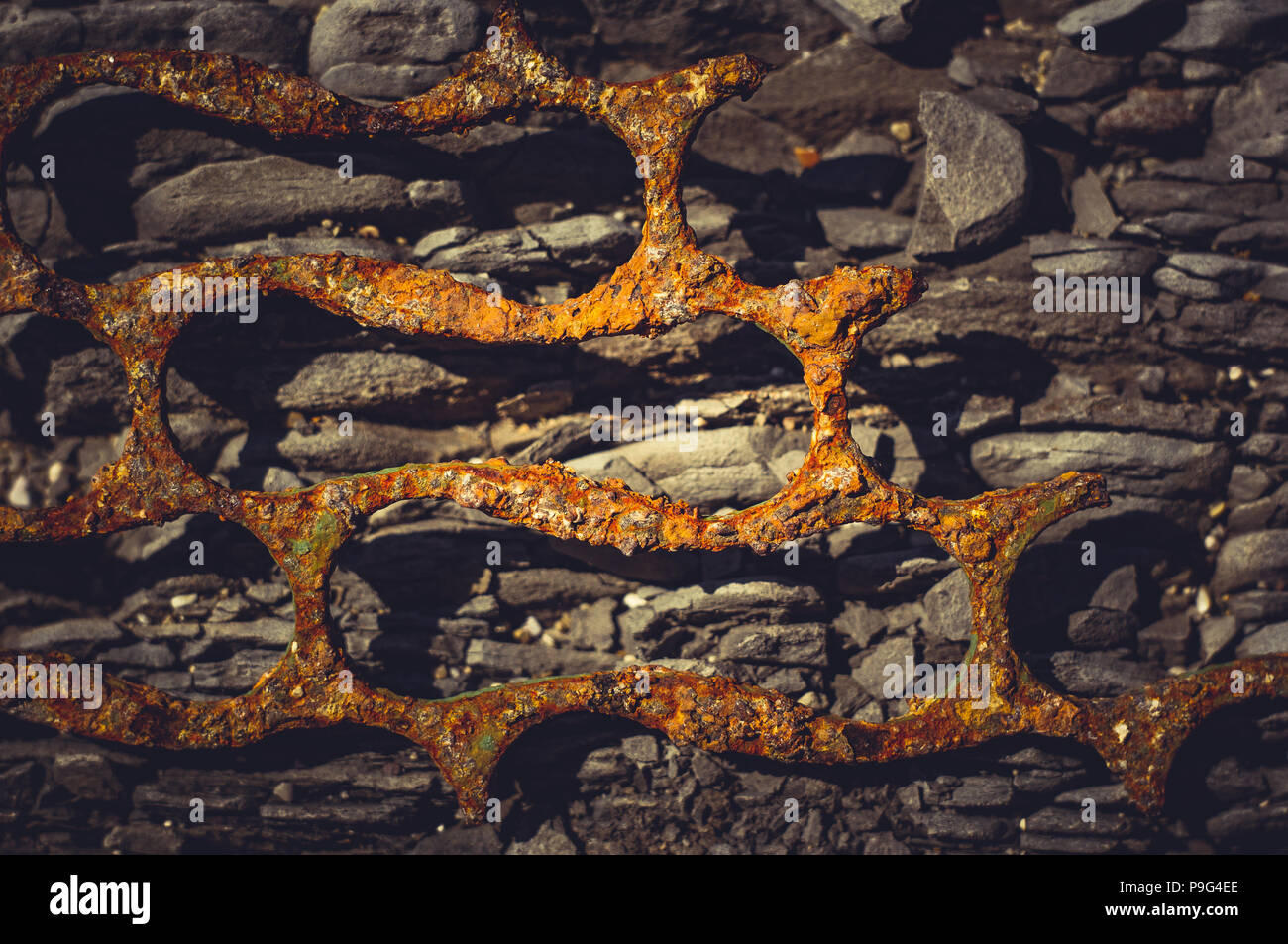 Very rusty metal on a gray cracked rock, bright sunlight, close up ...