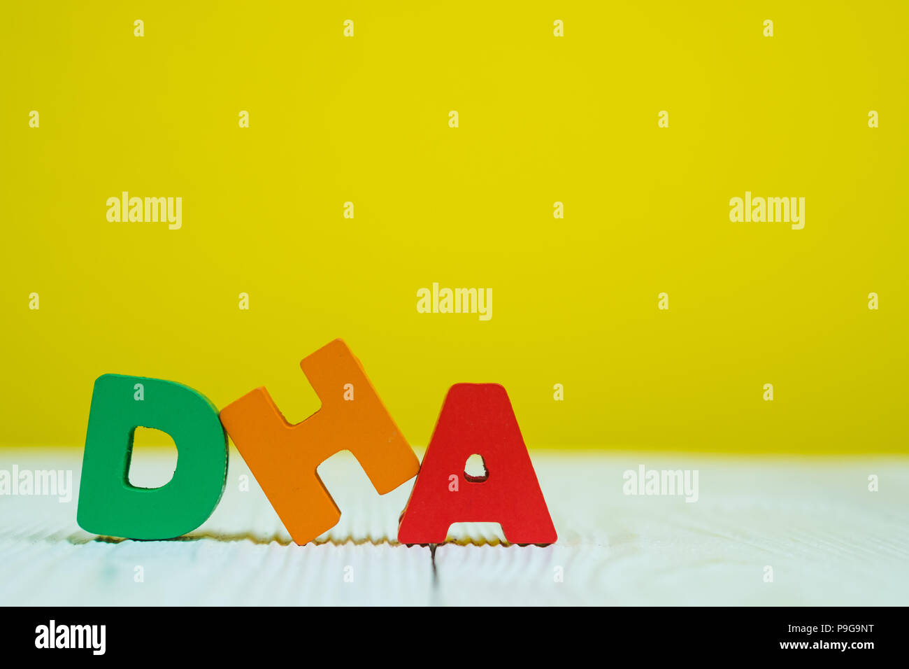 DHA text alphabet on white wooden table. yellow wall background with ...