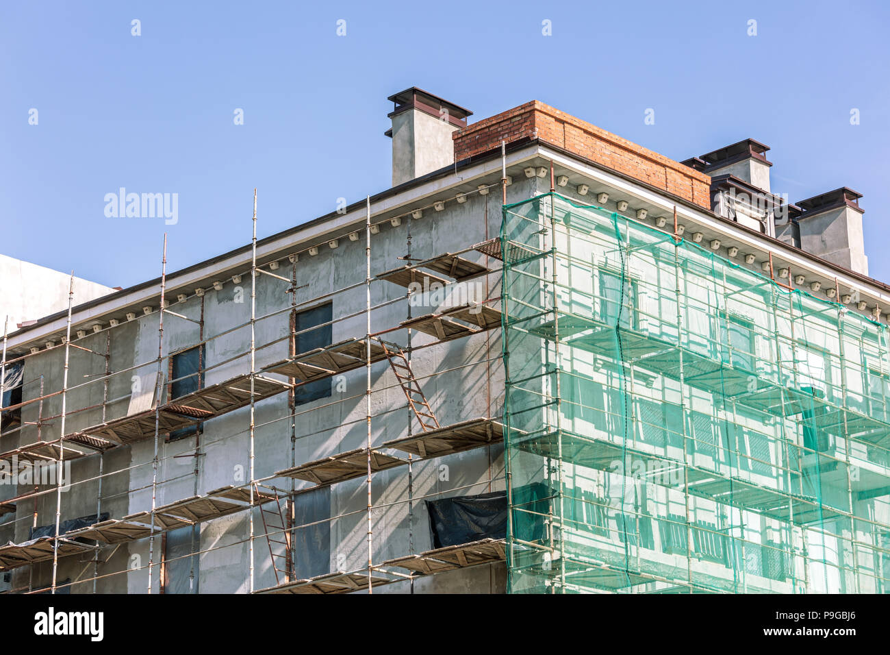 facade of a renovated building. scaffolding with green protective net ...