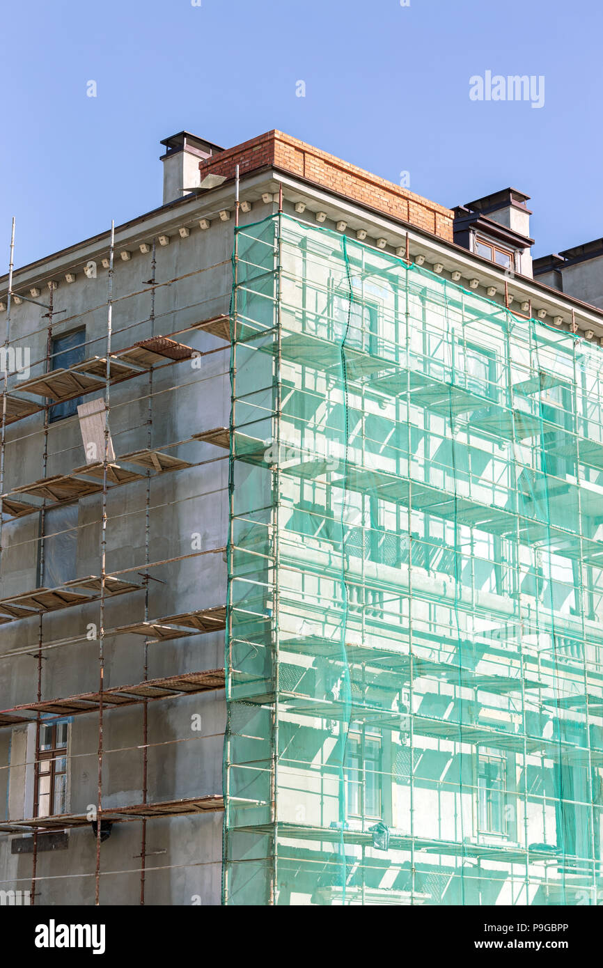 building exterior under renovation with scaffolding and green netting ...