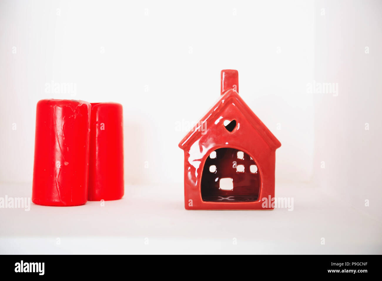 red ceramic house and two red candles on white background Stock Photo ...