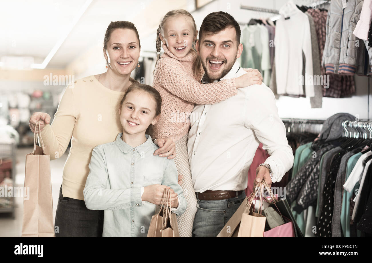 Young smiling family with two daughters holding bags after shopping in ...
