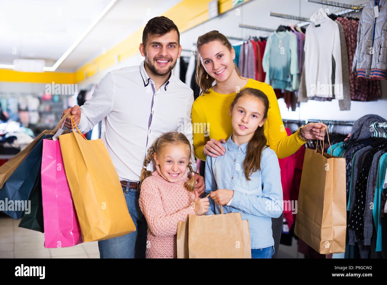 Young positive family with two daughters after shopping in shop. Focus ...