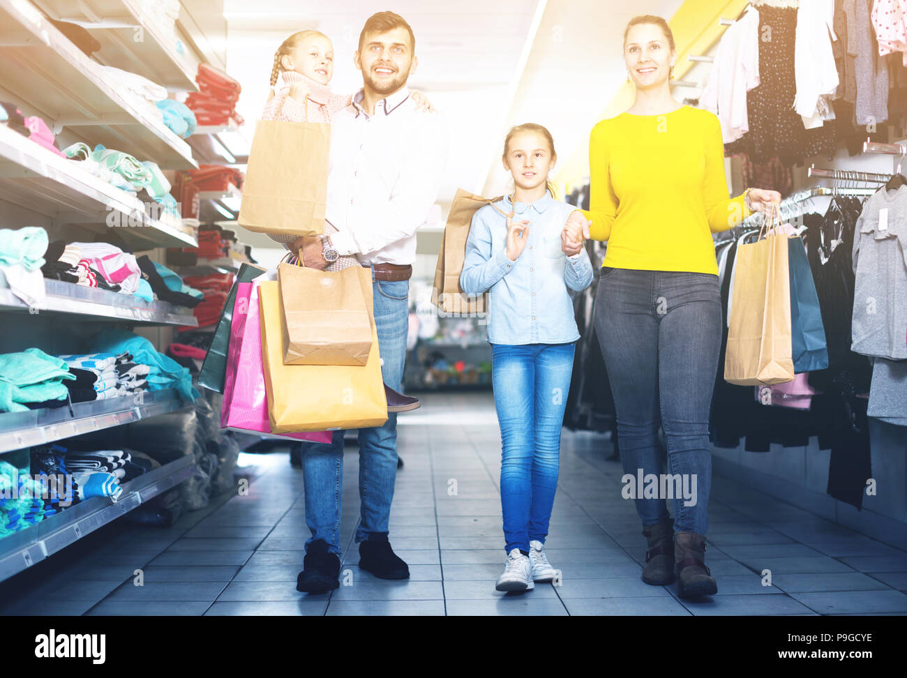 Young happy positive parents with two little girls shopping in mall ...