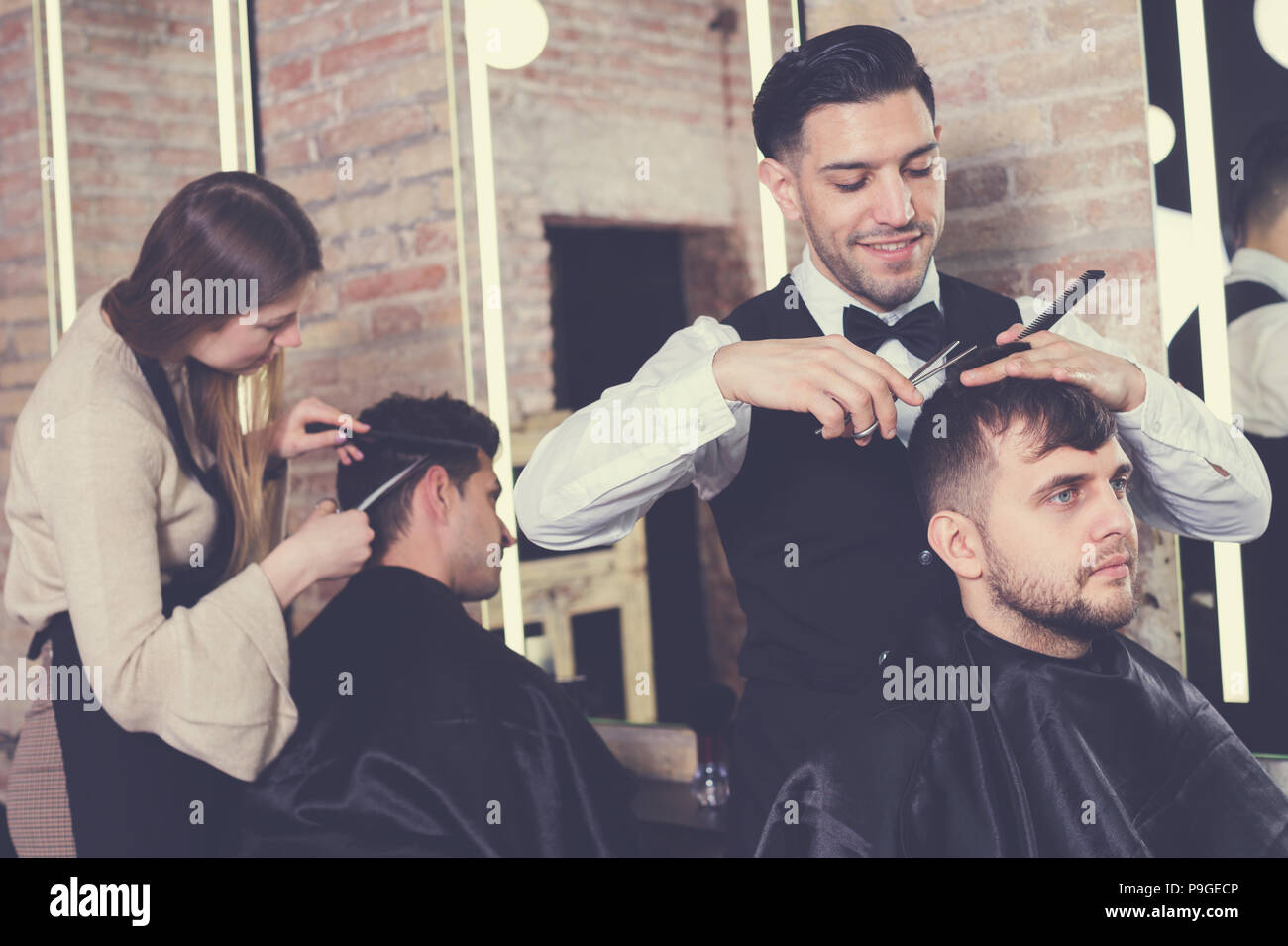 Skillful man barber making haircutting for male client in hair studio ...