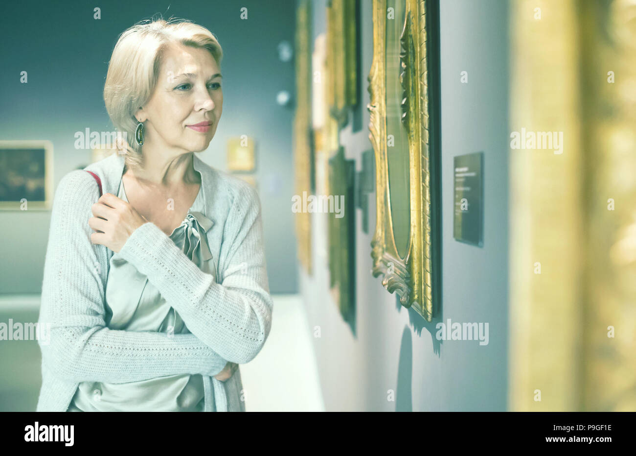 Glad cheerful positive smiling female visitor looking at artwork ...