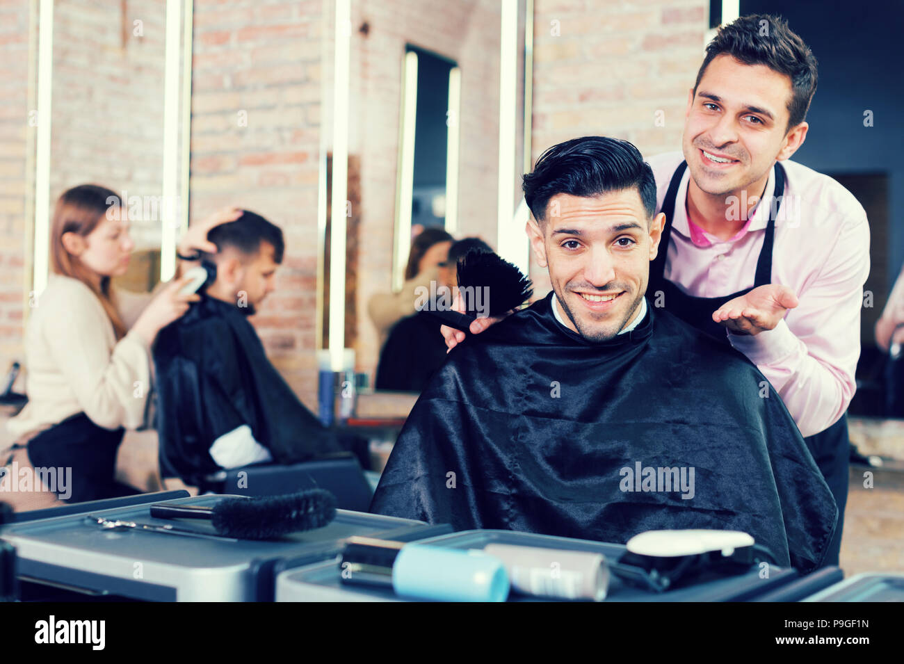 Professional hairstylist presenting result of his styling to male ...