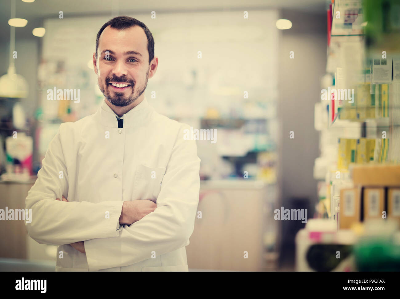Smiling happy cheerful male pharmacist demonstrating assortment of ...