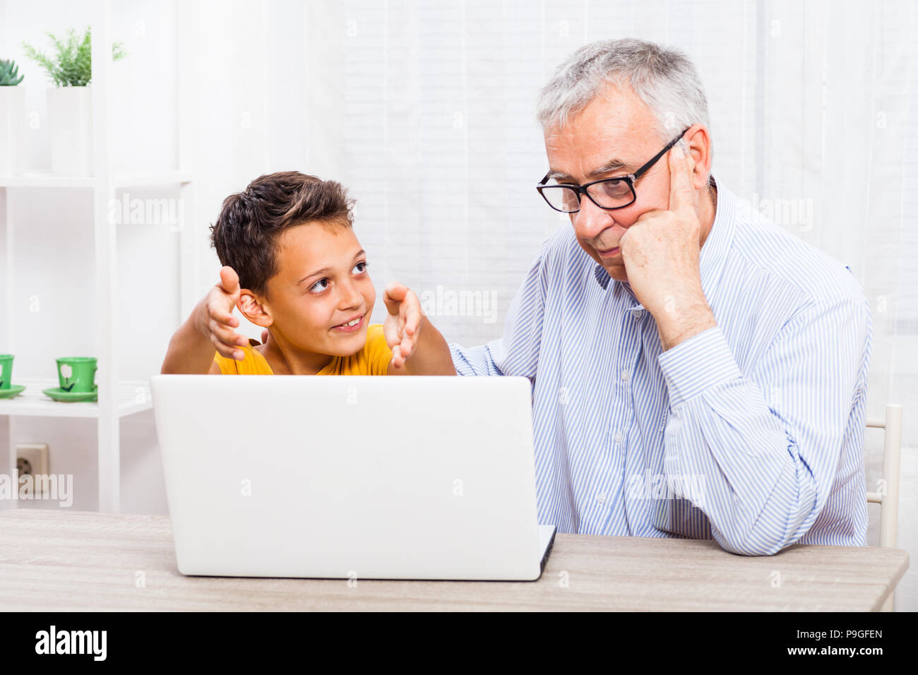 Grandson is teaching his grandfather to use laptop computer Stock Photo ...
