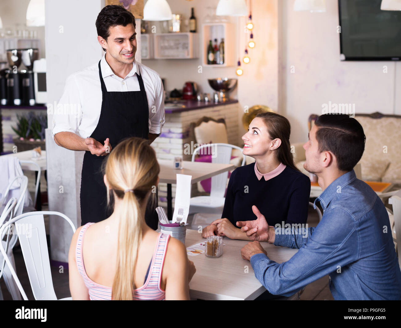 Guests of comfy confectionery giving order to welcoming waiter Stock ...