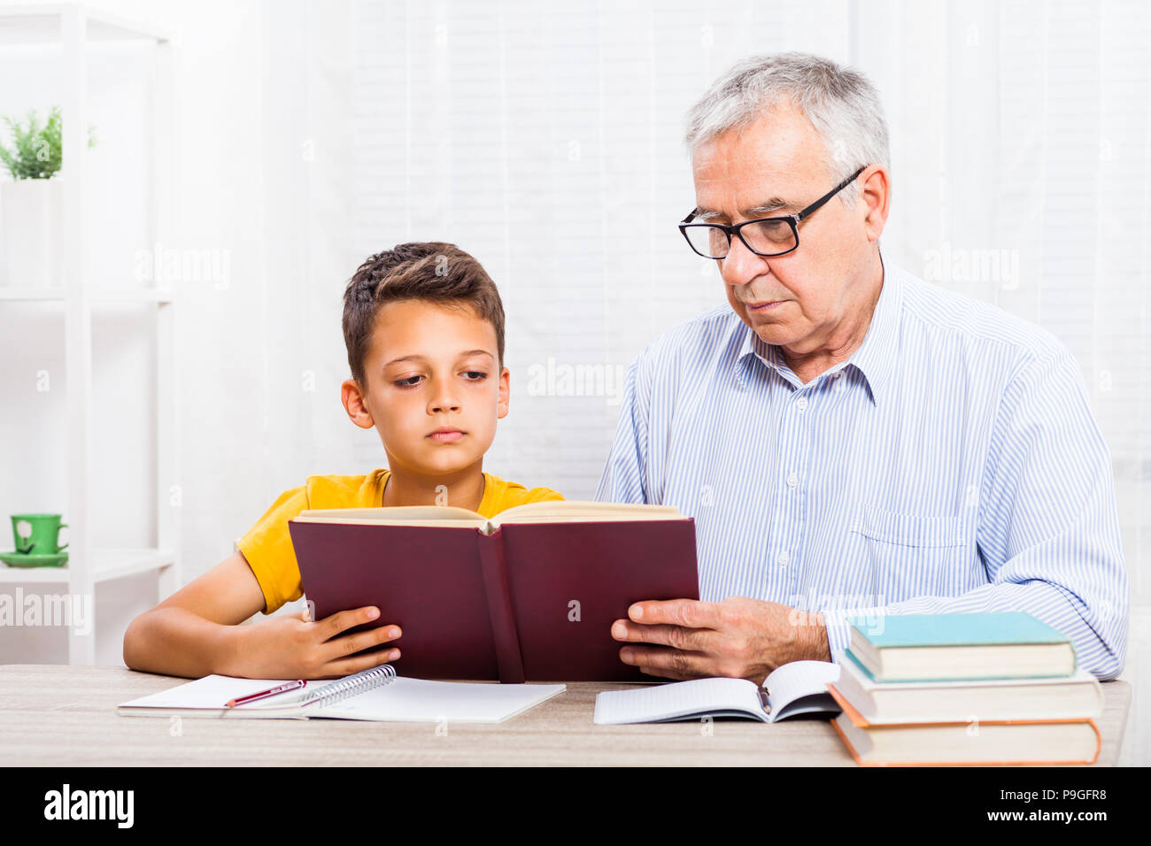 Grandfather and grandson are reading book at home Stock Photo - Alamy