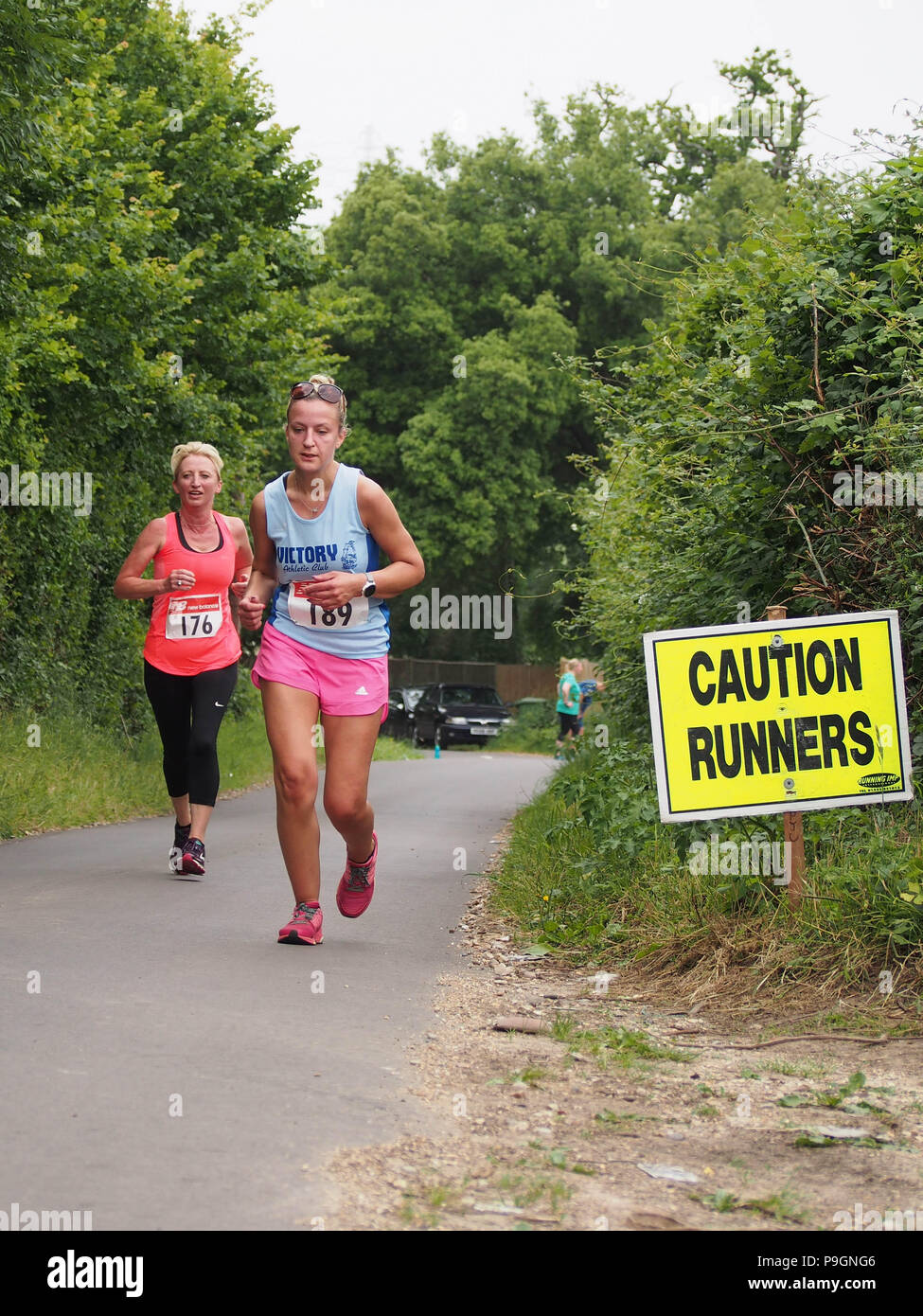 A "caution runners" sign with female runners taking part in a road race ...