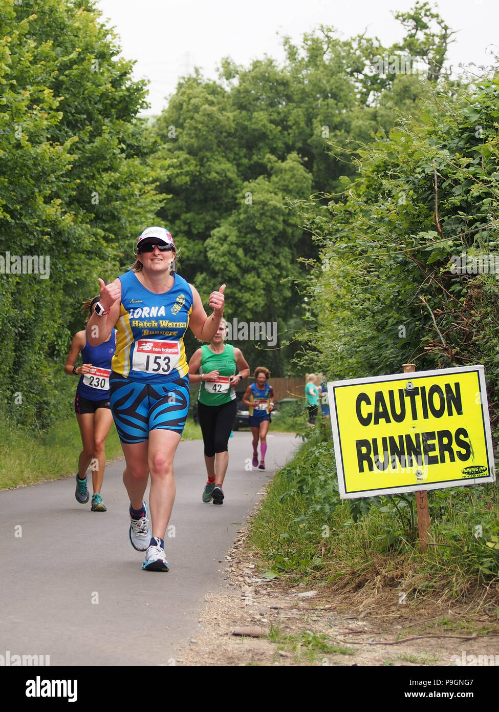 A "caution runners" sign with female runners taking part in a road race ...