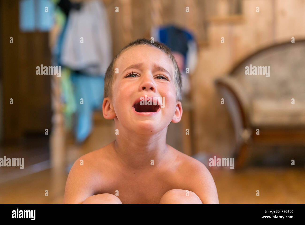 Little boy sitting on the floor, he's upset and crying. The child is ...
