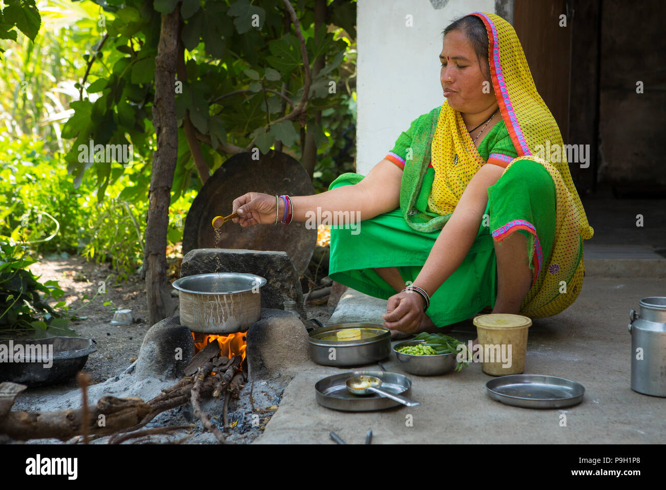 A woman cooking lunch outside on an open fire at their home in ...