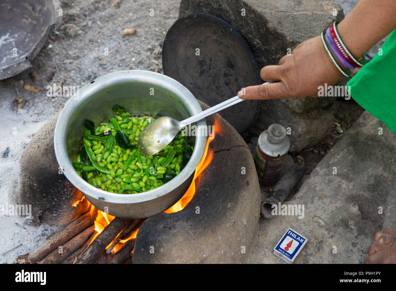 A woman cooking lunch outside on an open fire at their home in ...
