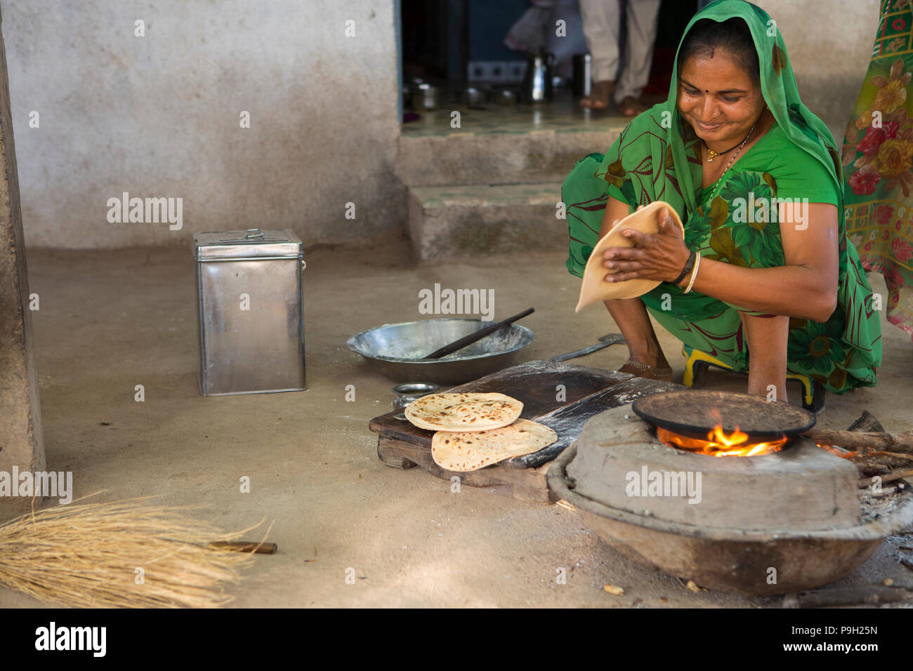 A woman making chapatis on an open wood fire at their home in Ahmedabad ...