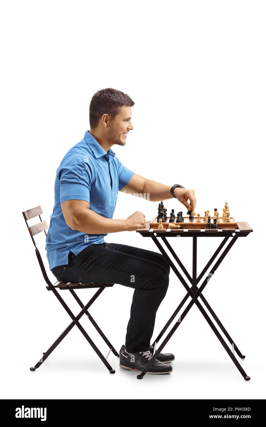 Young guy seated at a table playing chess isolated on white background ...