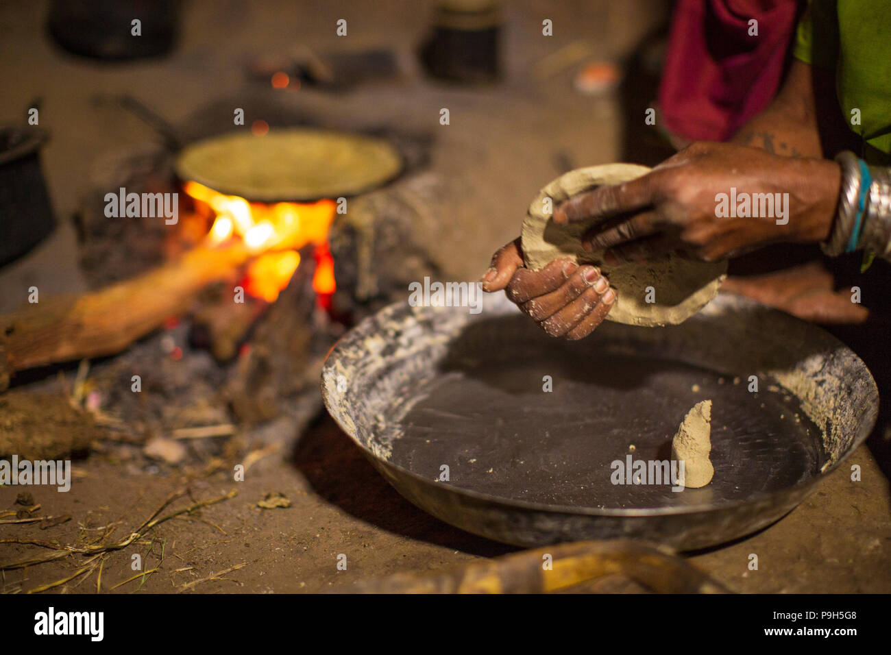 A woman making chapatis on an open fire in her kitchen, Sendhwa, India ...
