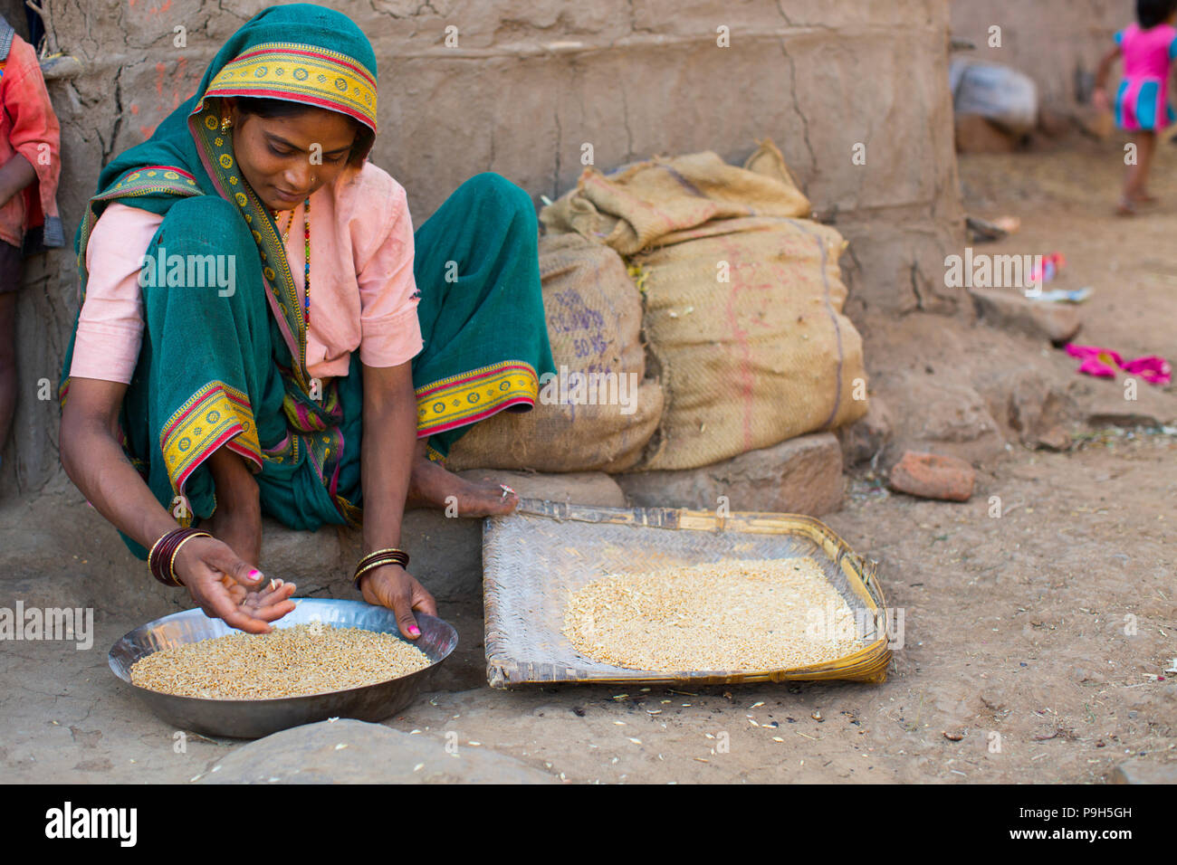 A women checks her grain before making flour outside her home in ...