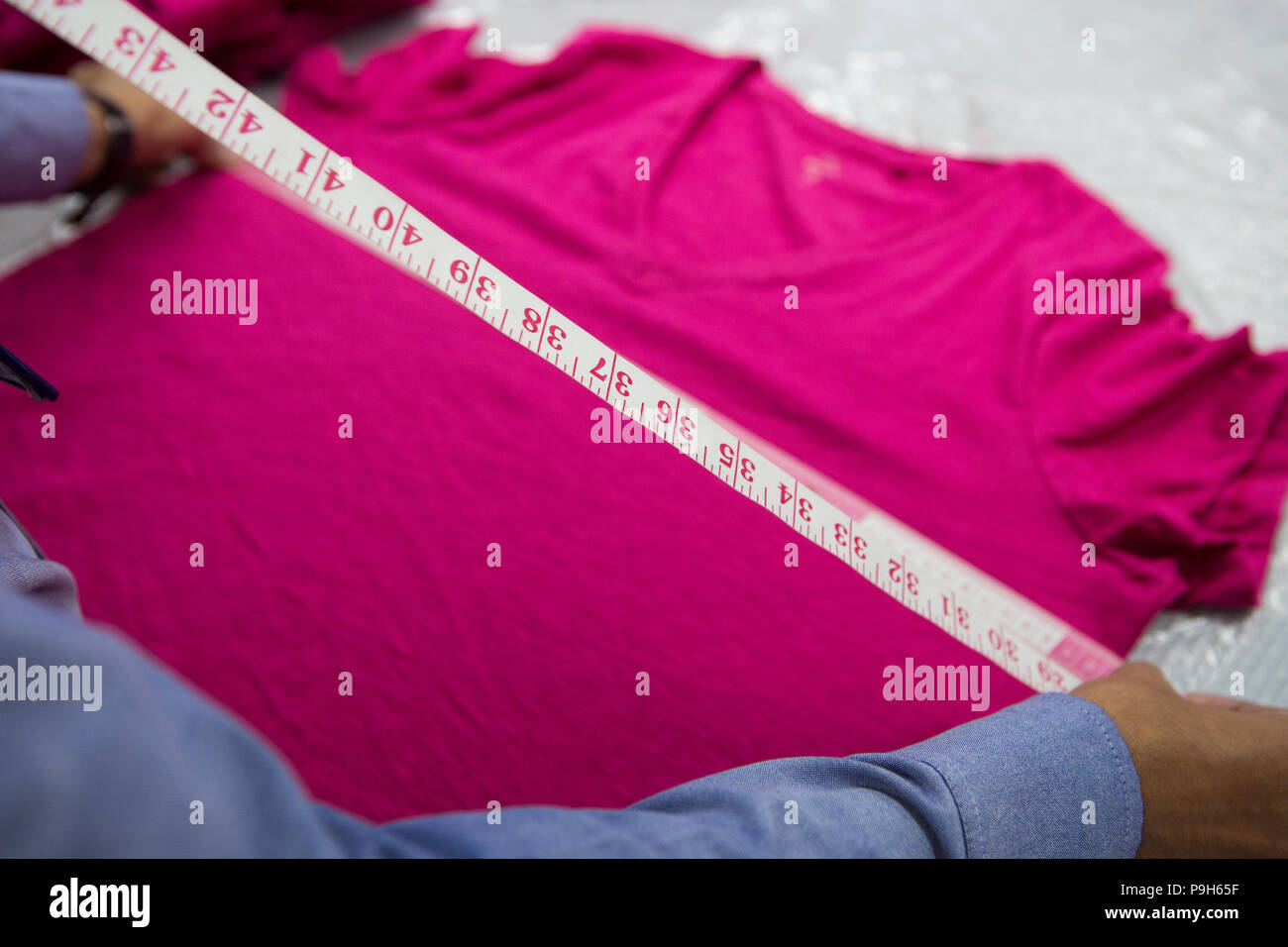 A man checks the quality of T-shirts on a production line in a garment ...