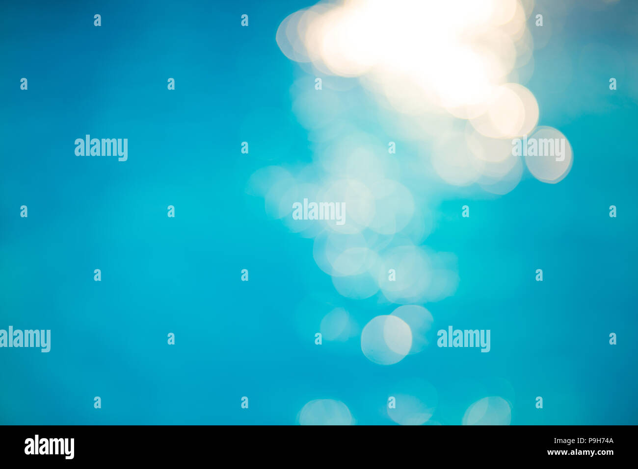 Soft focus bokeh light effects over a rippled, blue water background in ...