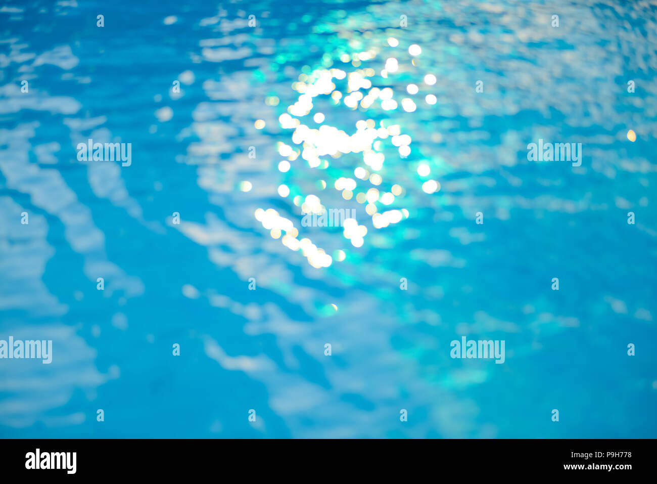 Soft focus bokeh light effects over a rippled, blue water background in ...