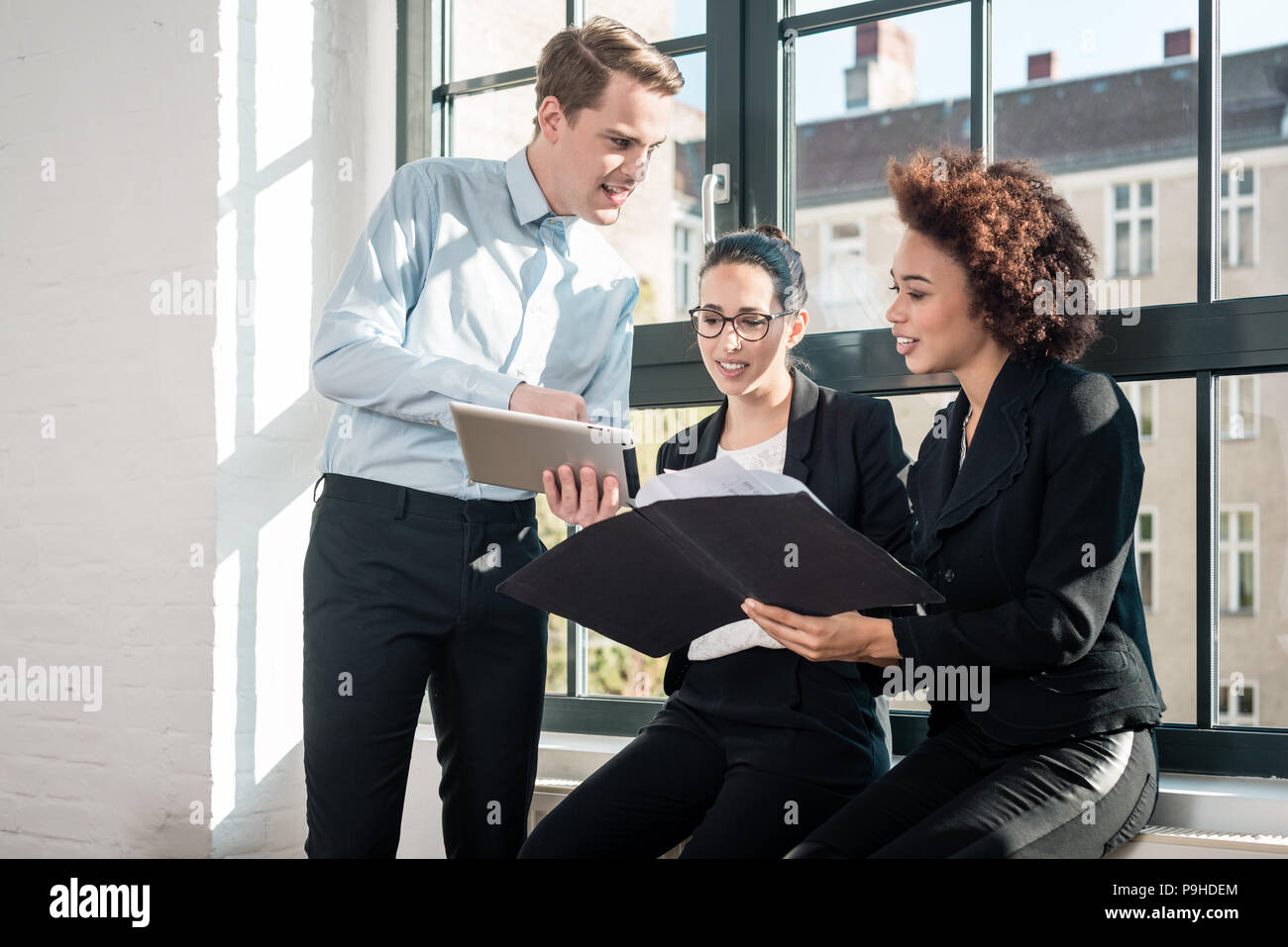 Three young cheerful employees smiling in a modern office Stock Photo ...