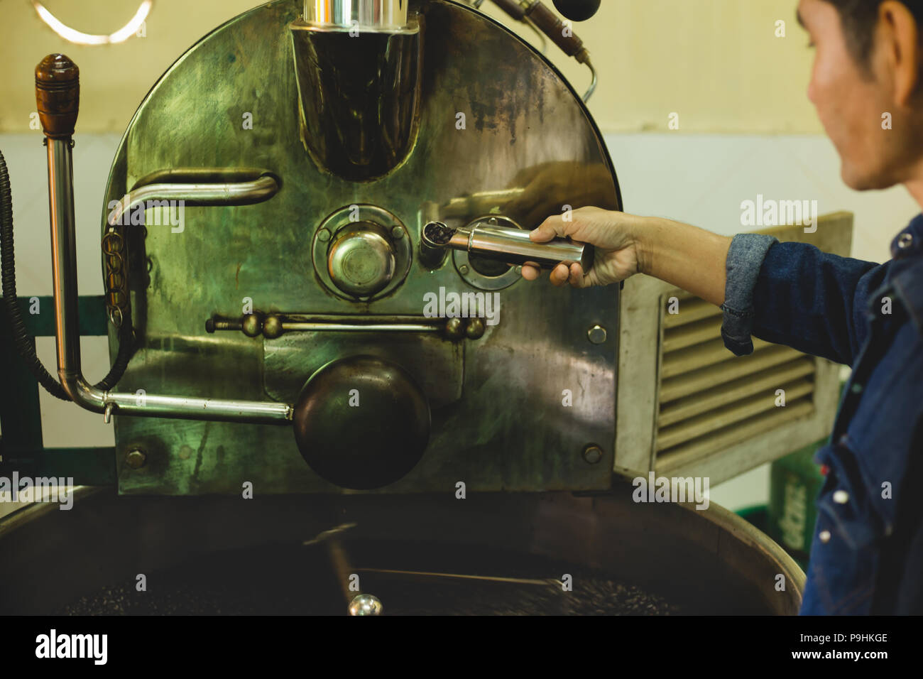 Hand of roaster holding a probe of fresh roasted coffee beans Stock ...
