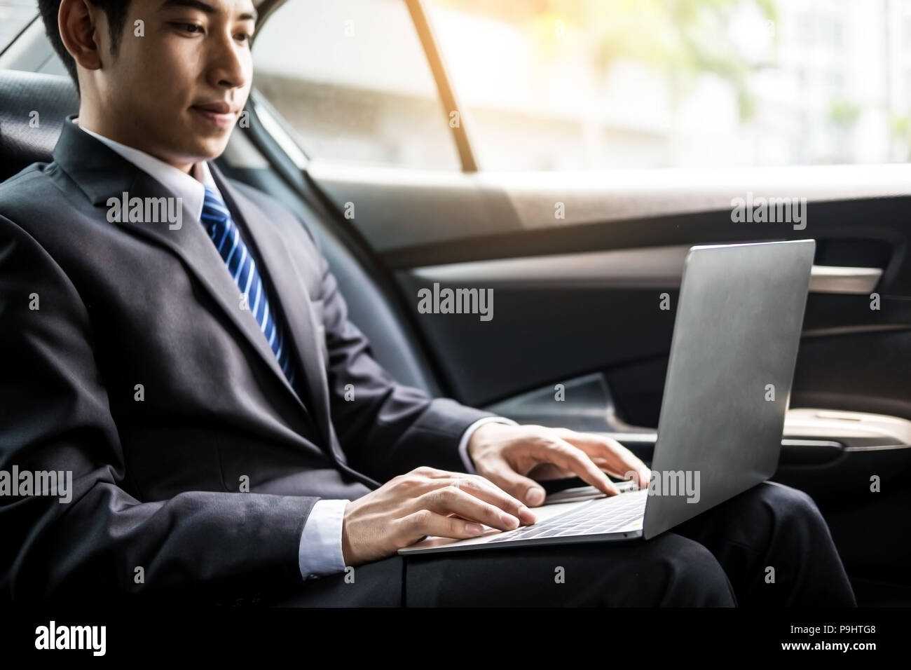 Handsome Young businessman using laptop and sitting in back seat of car ...