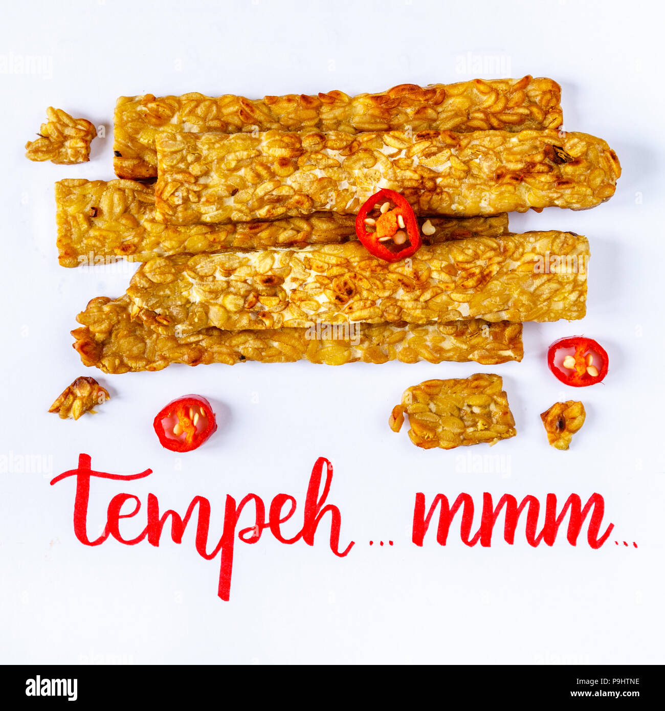 Fried tempeh decorated with sliced chilly. TEMPEH MMM caption. Top view ...