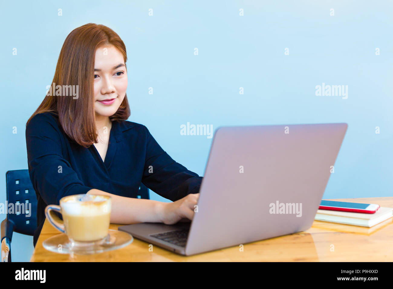 Happy attractive young Asian businesswoman working on her laptop ...