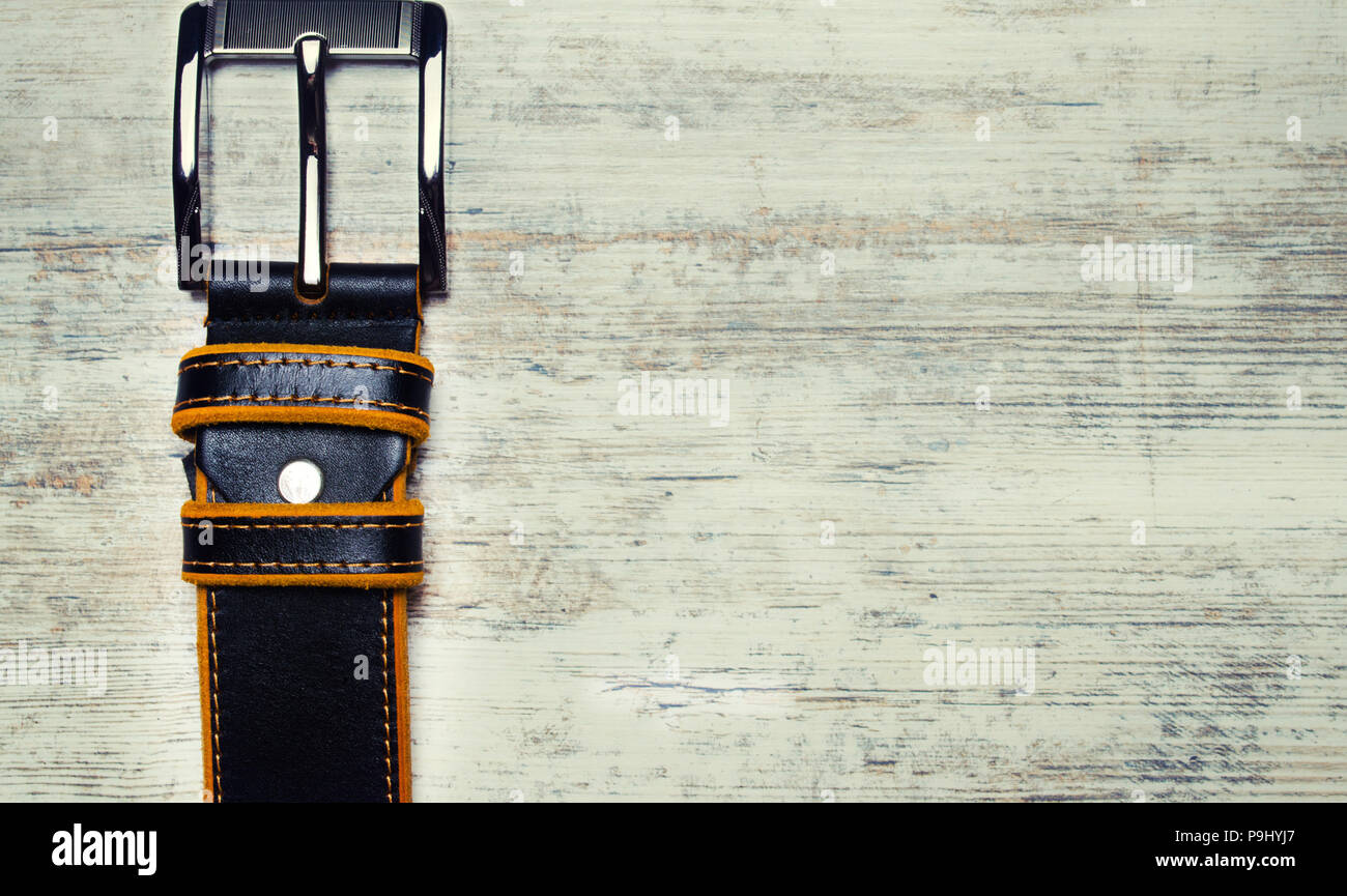 twisted black male leather belt on a white wooden background, top view ...