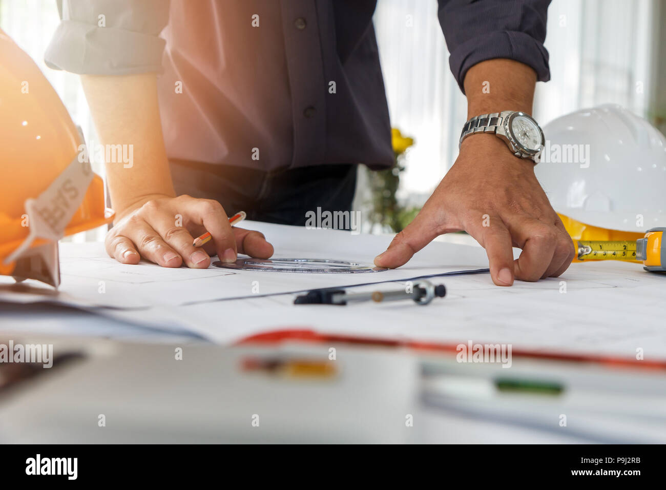 Architect or engineer using pencil and protractor working on blueprint ...