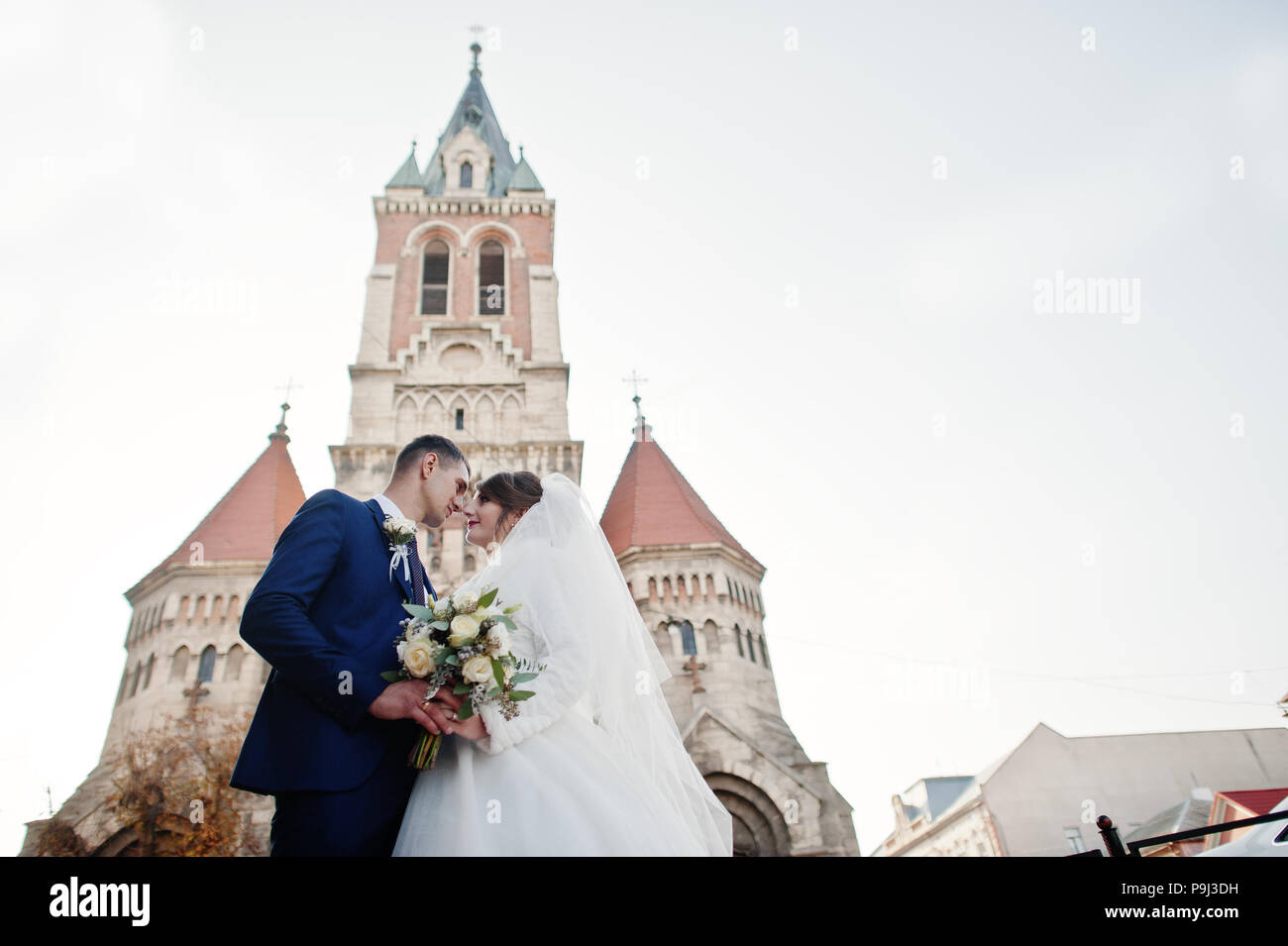 Newly married couple posing next to the old church in the town on a ...