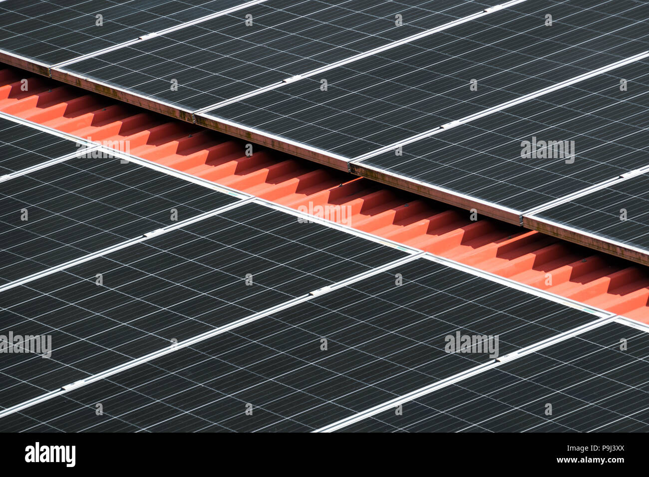 Sun reflection on a solar roof. black solar panel closeup on red roof ...