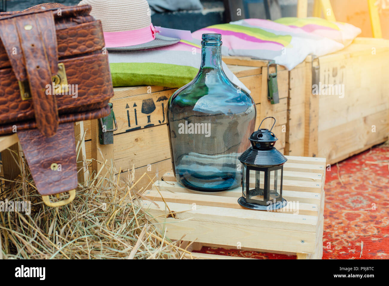 Vintage rustic composition with lantern, candle, big bottle, wooden ...