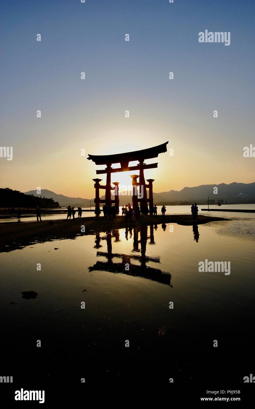 sunset behind the floating Tori gate at the Itsukushima Shinto Shrine ...